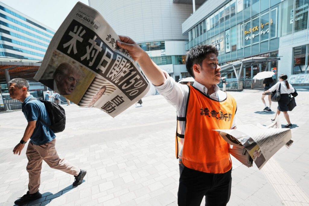 A staff member distributes an extra edition of the Yomiuri Shimbun newspaper reporting that President Donald Trump announced a trade framework with Japan on Tuesday, Wednesday, July 23, 2025, in Tokyo. The headline reads "U.S., a 15% tax on goods imported from Japan."