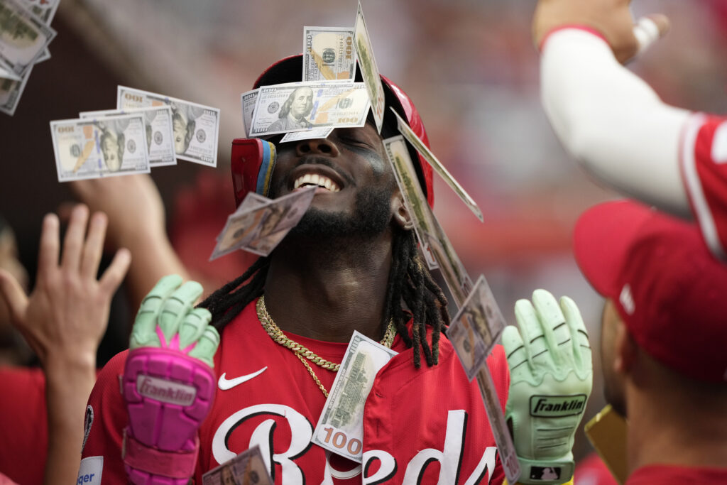 Teammates shower Cincinnati Reds' Elly De La Cruz with play money in the dugout after his two-run homer during the third inning of a baseball game against the Atlanta Braves, in Cincinnati, Thursday, July 31, 2025.